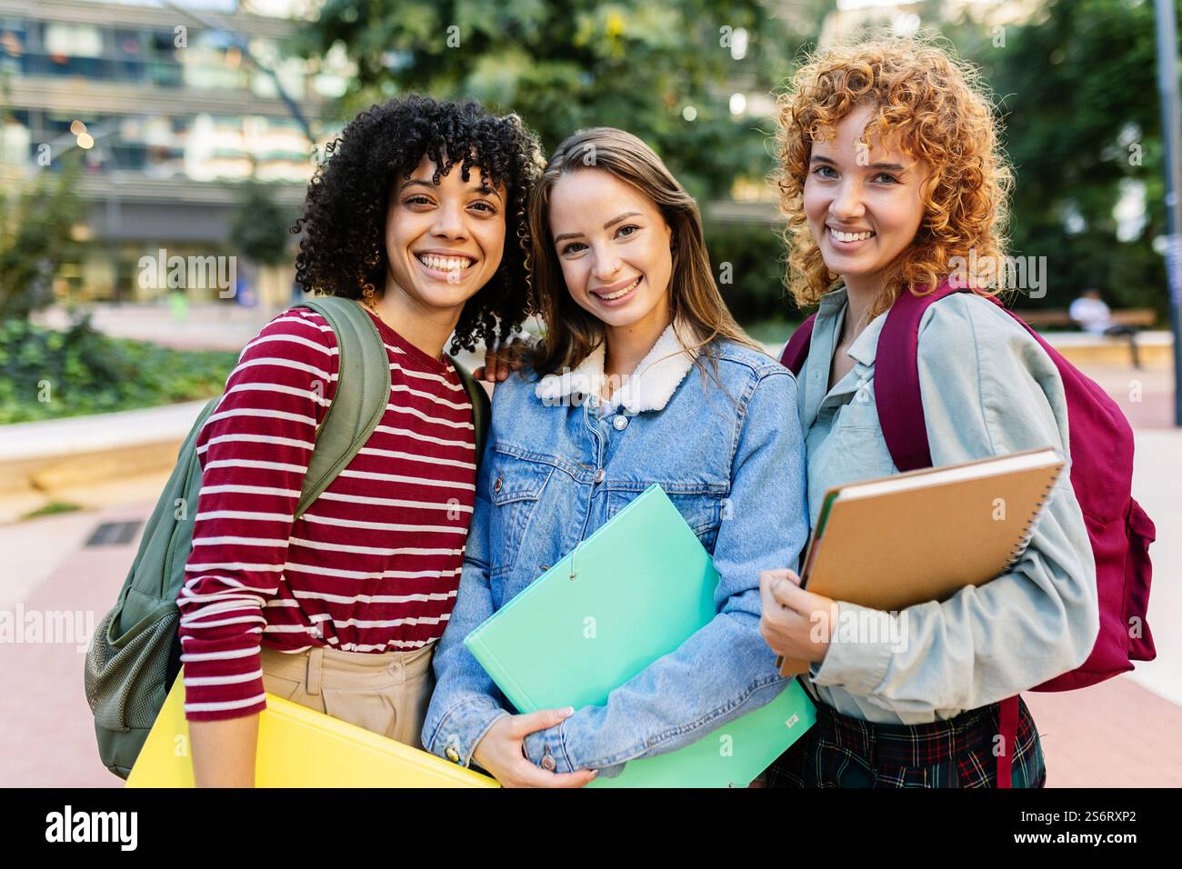 Three young university female students smiling together at camera on ...