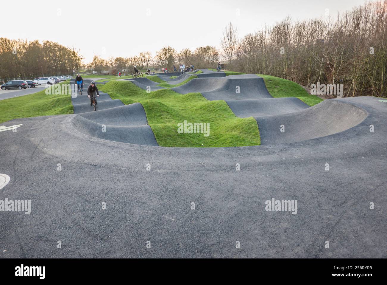 children and teenagers ride their bikes over a pump track, Germany ...