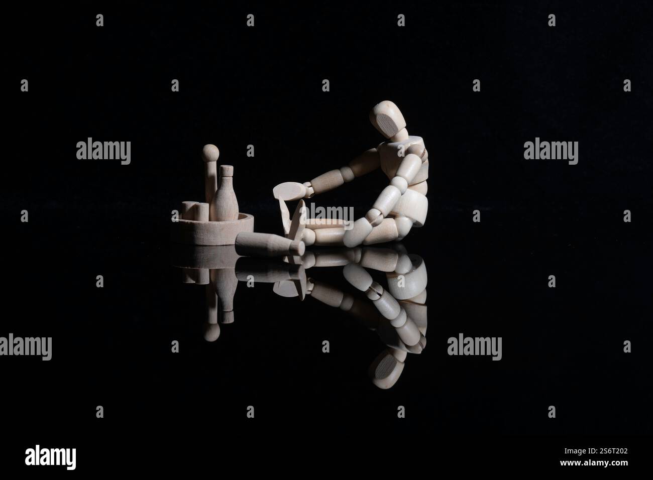 Sitting Wooden Figure Looking Down at Wood Bottles Stock Photo - Alamy