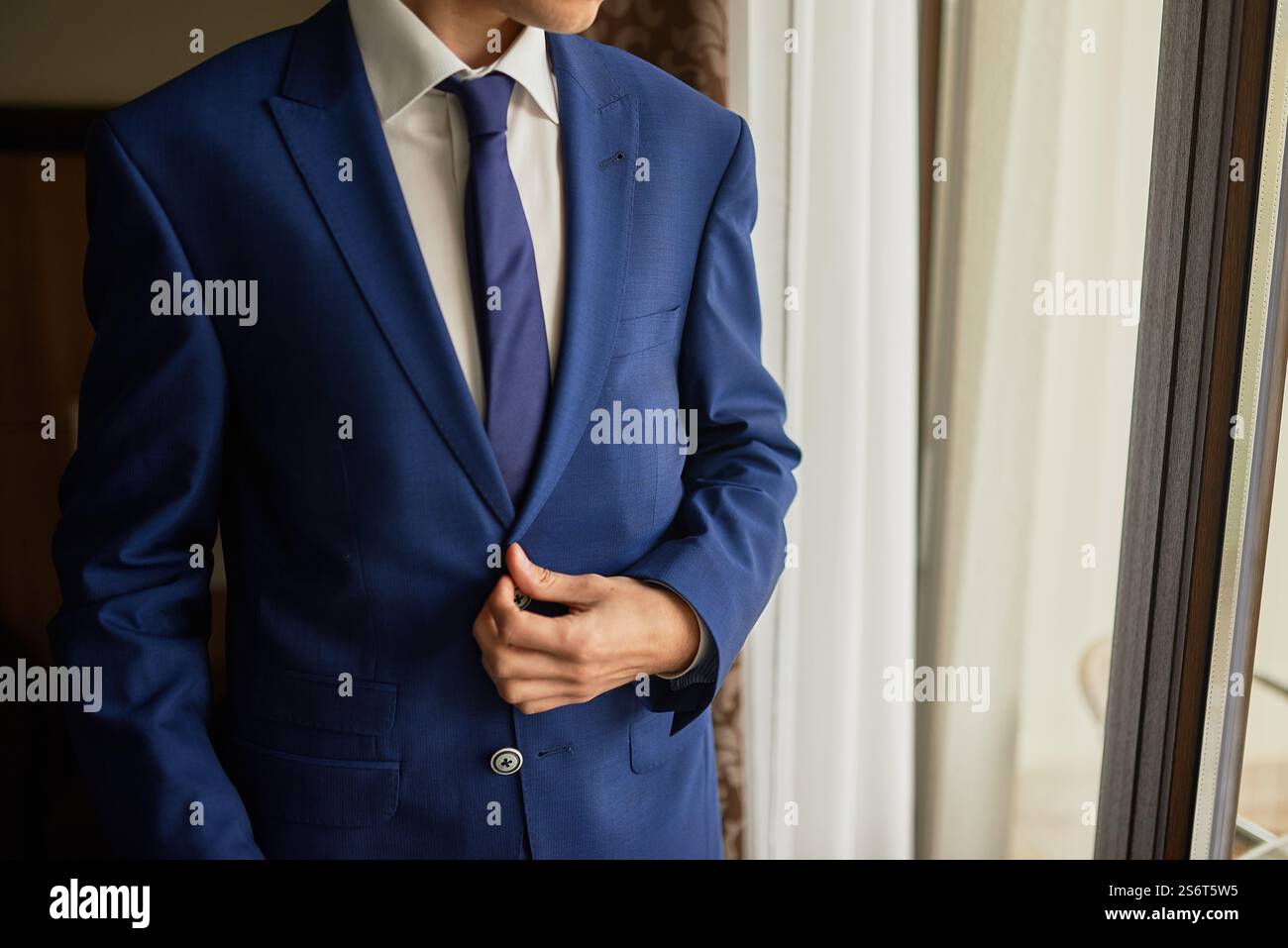 Individual in blue suit jacket, adjusting attire, formal clothing ...