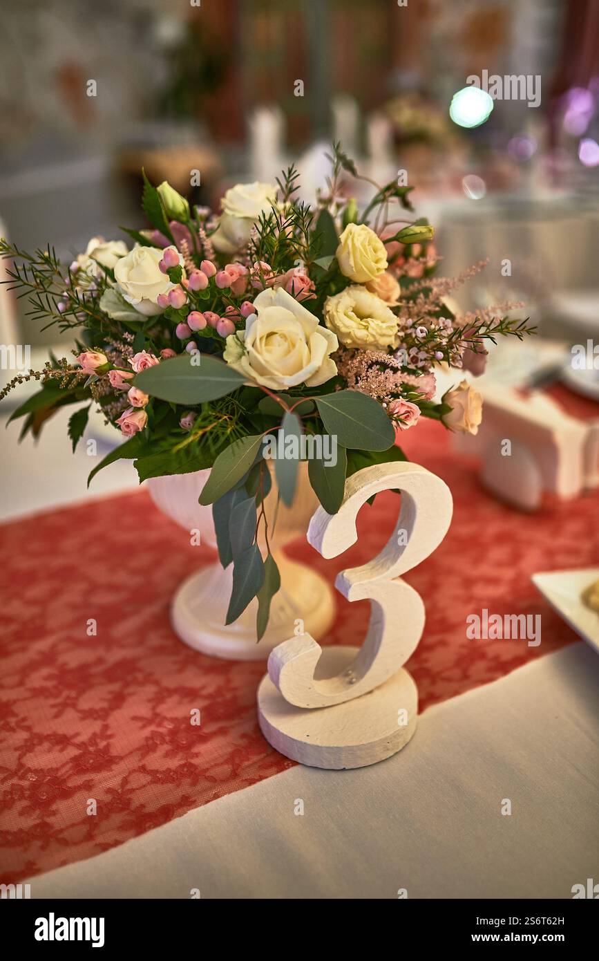 Wedding centerpiece with elegant roses and table number three, featuring pink flowers, romantic ...