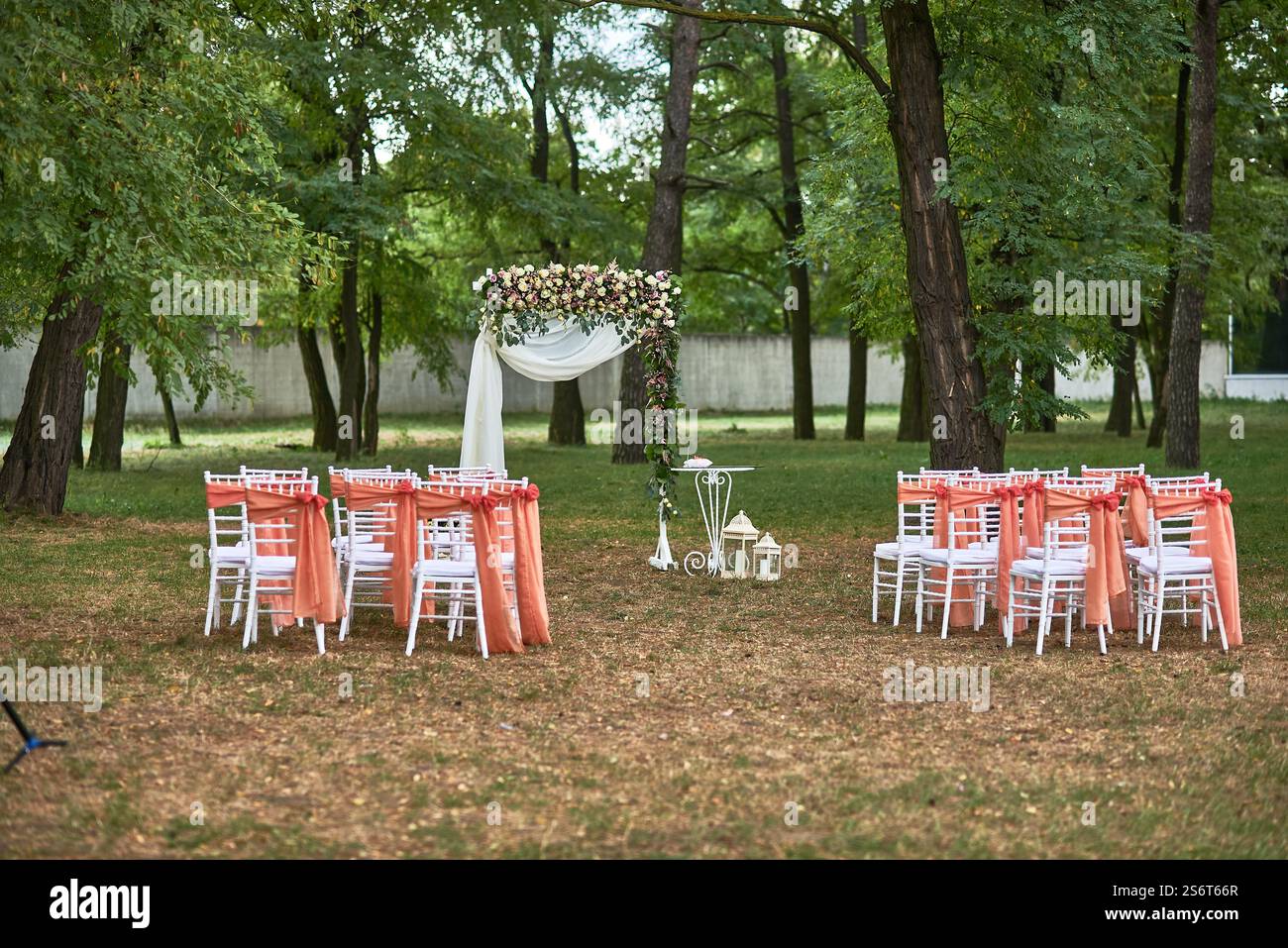 Wedding ceremony setup outdoors featuring floral arch and decorated ...