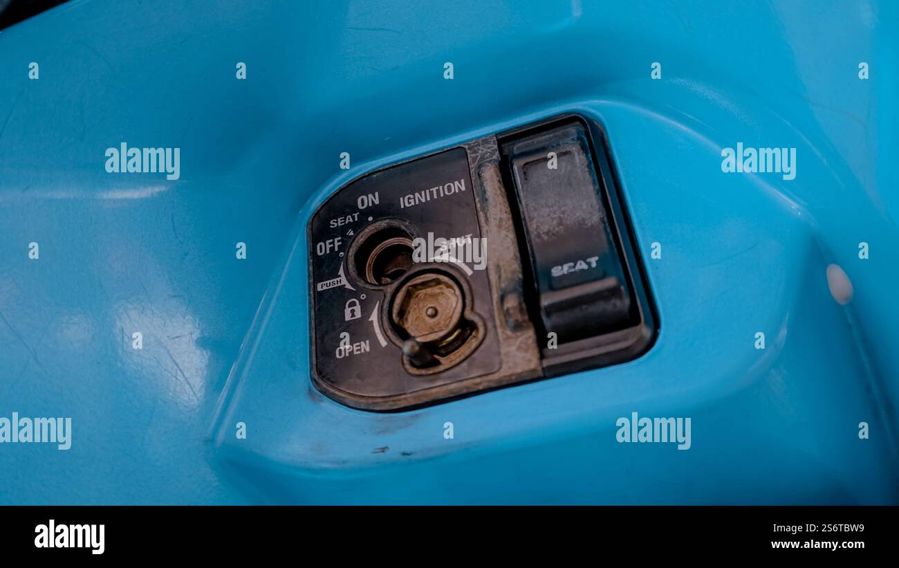 Close up of a scooter ignition switch with a blue background, showing ...