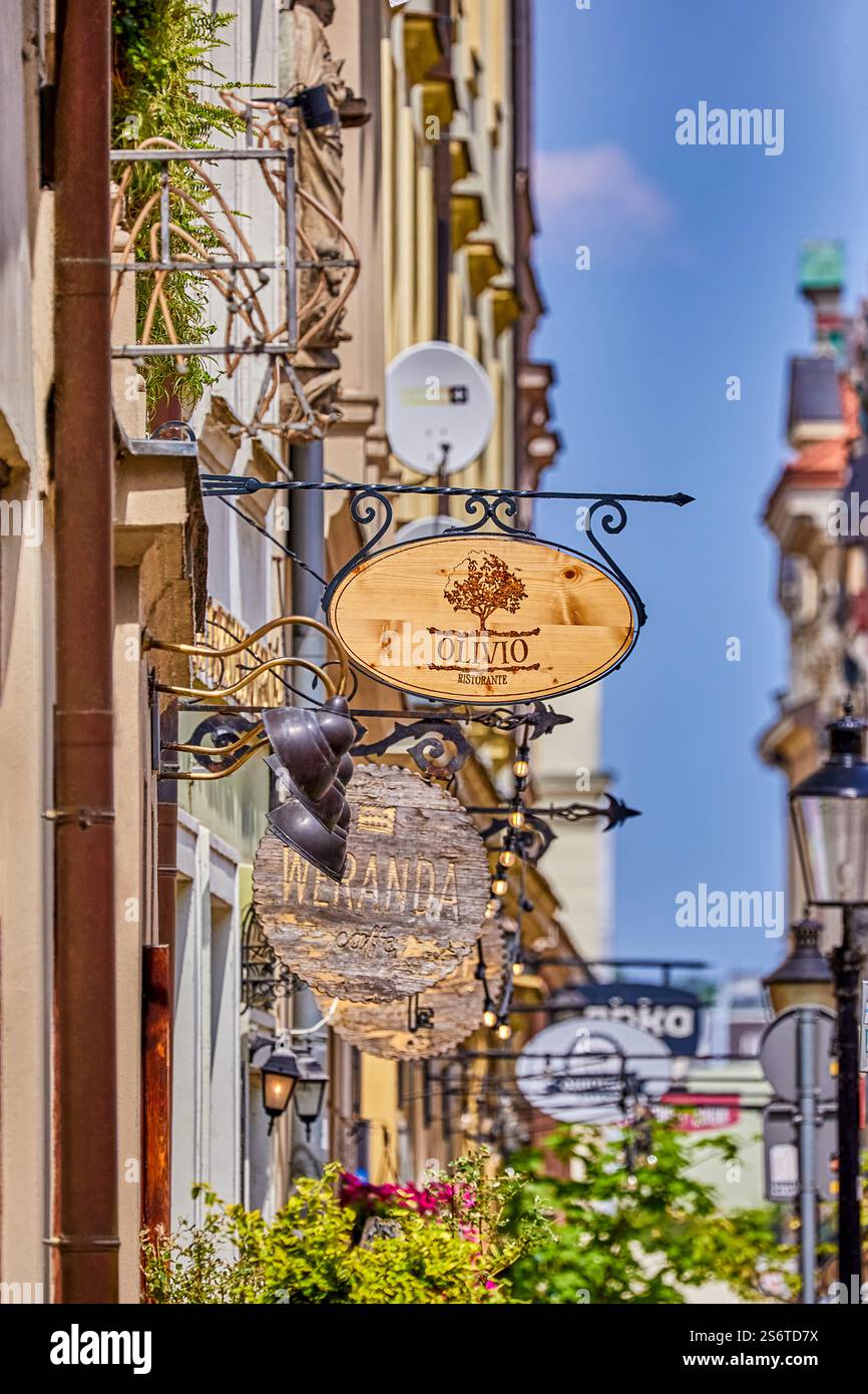 Wrought-iron signage amongst many shop signs on side of building in the ...