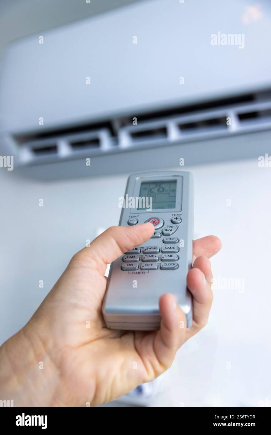 Hand operating an air conditioning remote control Stock Photo - Alamy