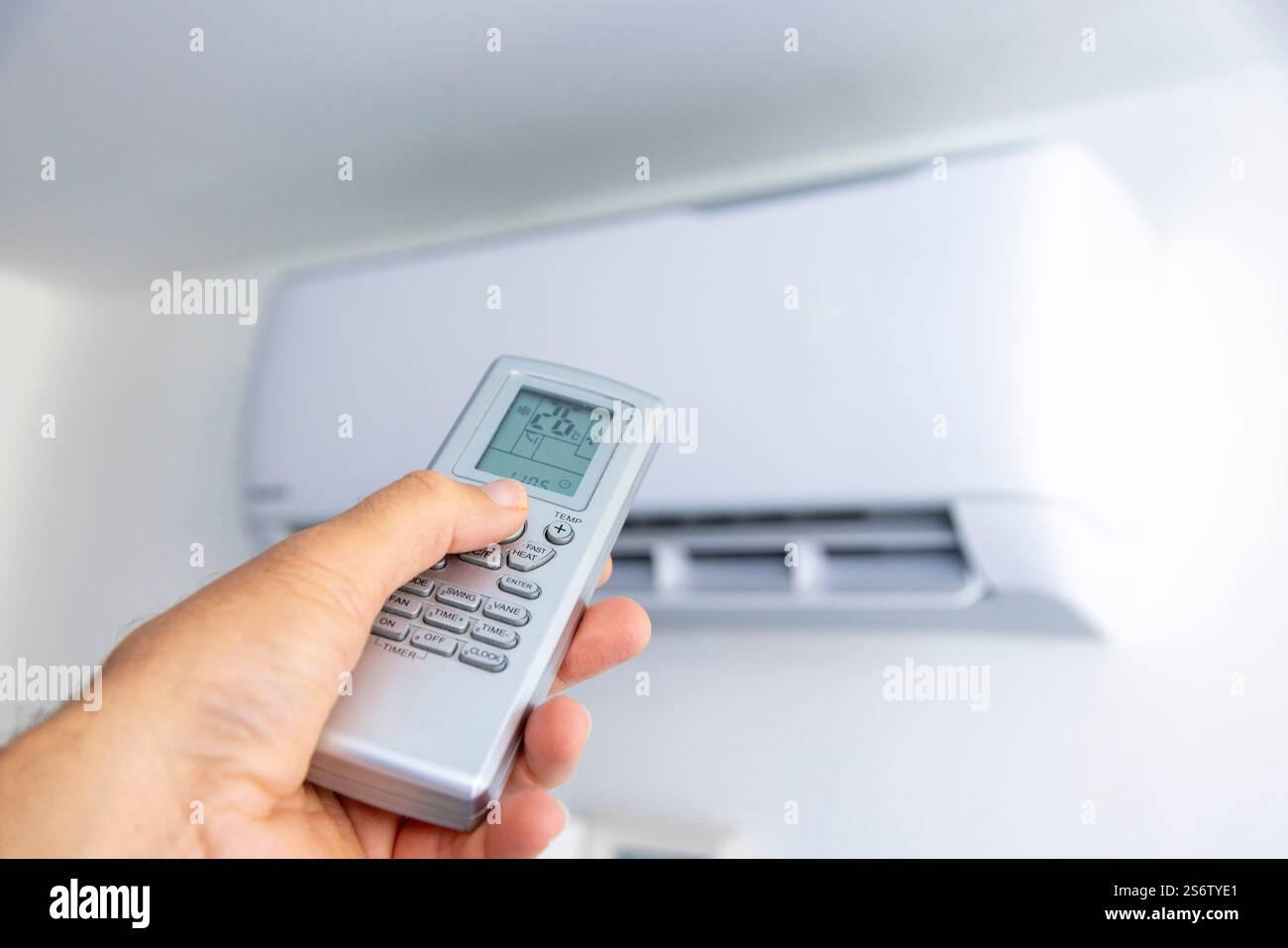 Hand operating an air conditioning remote control Stock Photo - Alamy