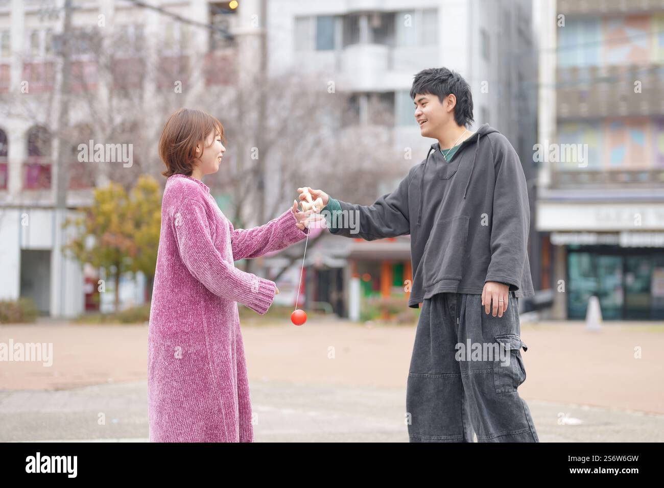 A Japanese man and woman in their 20s are playing kendama, a ...