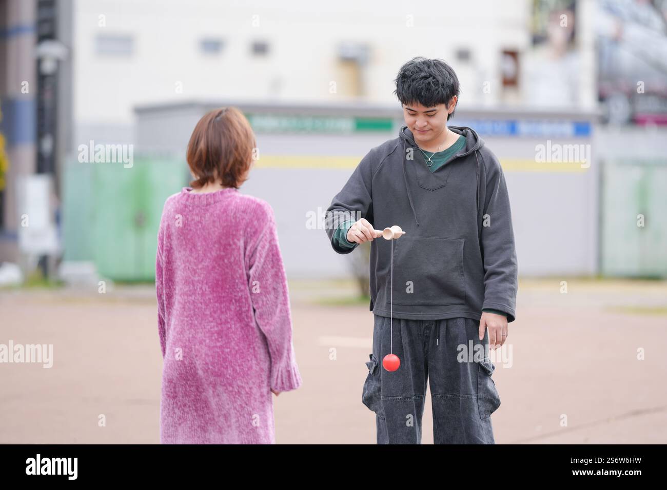 A Japanese man and woman in their 20s are playing kendama, a ...