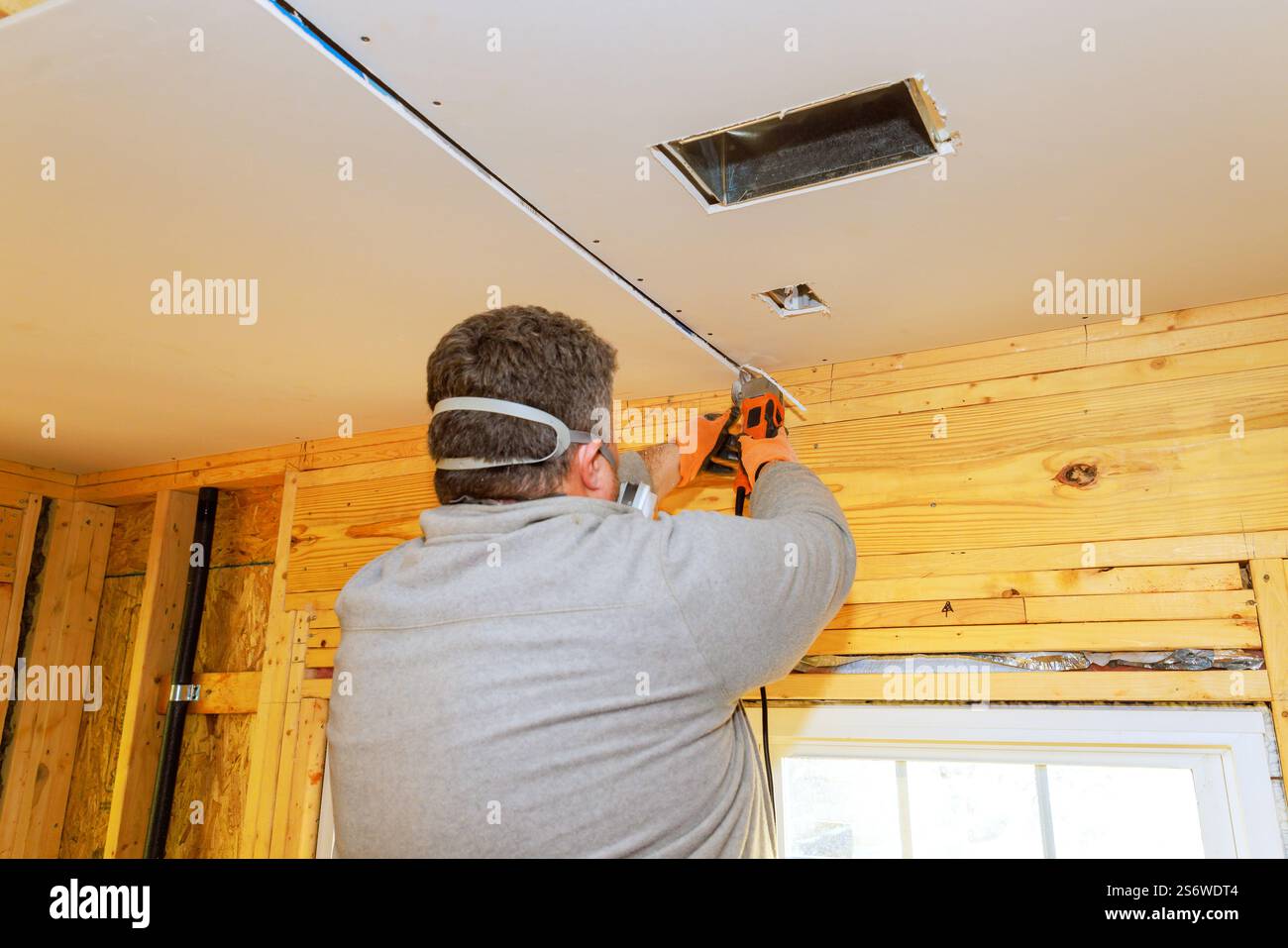 Contractor is cutting drywall on ceiling, installing drywall while ...