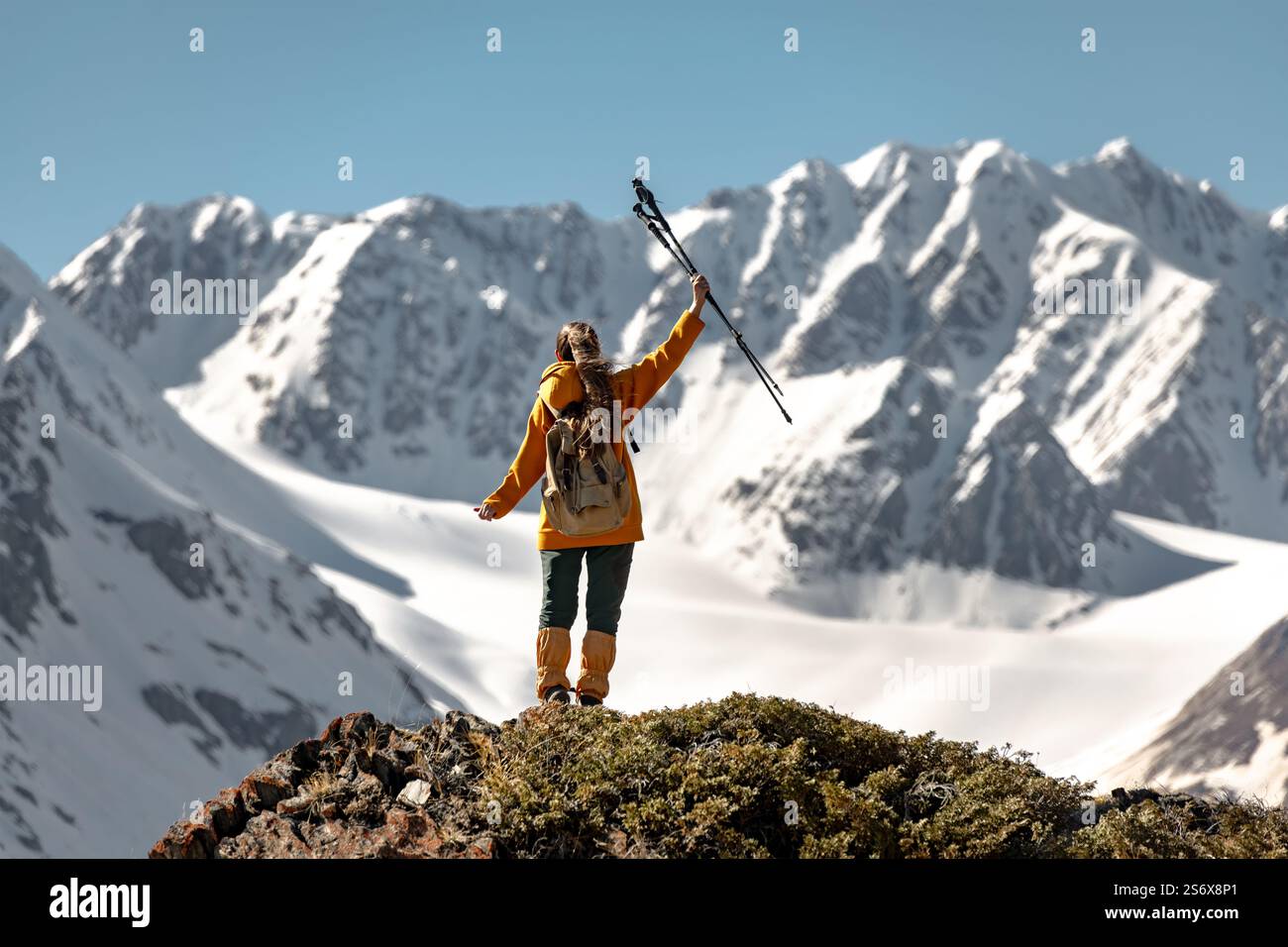 Happy woman hiker is standing with hiking poles and backpack in winner ...