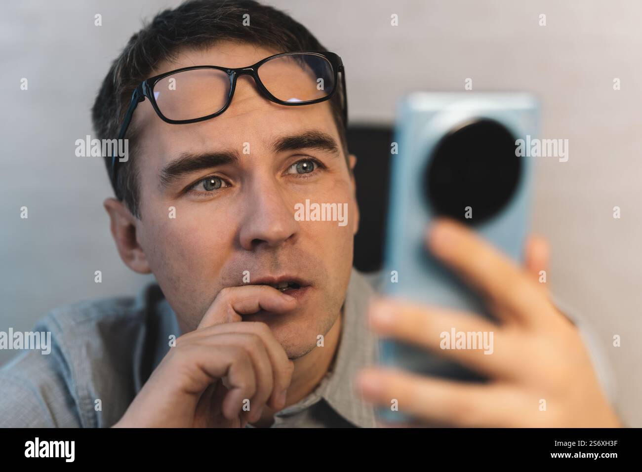 A young, handsome office employee looks at the screen of his smartphone ...