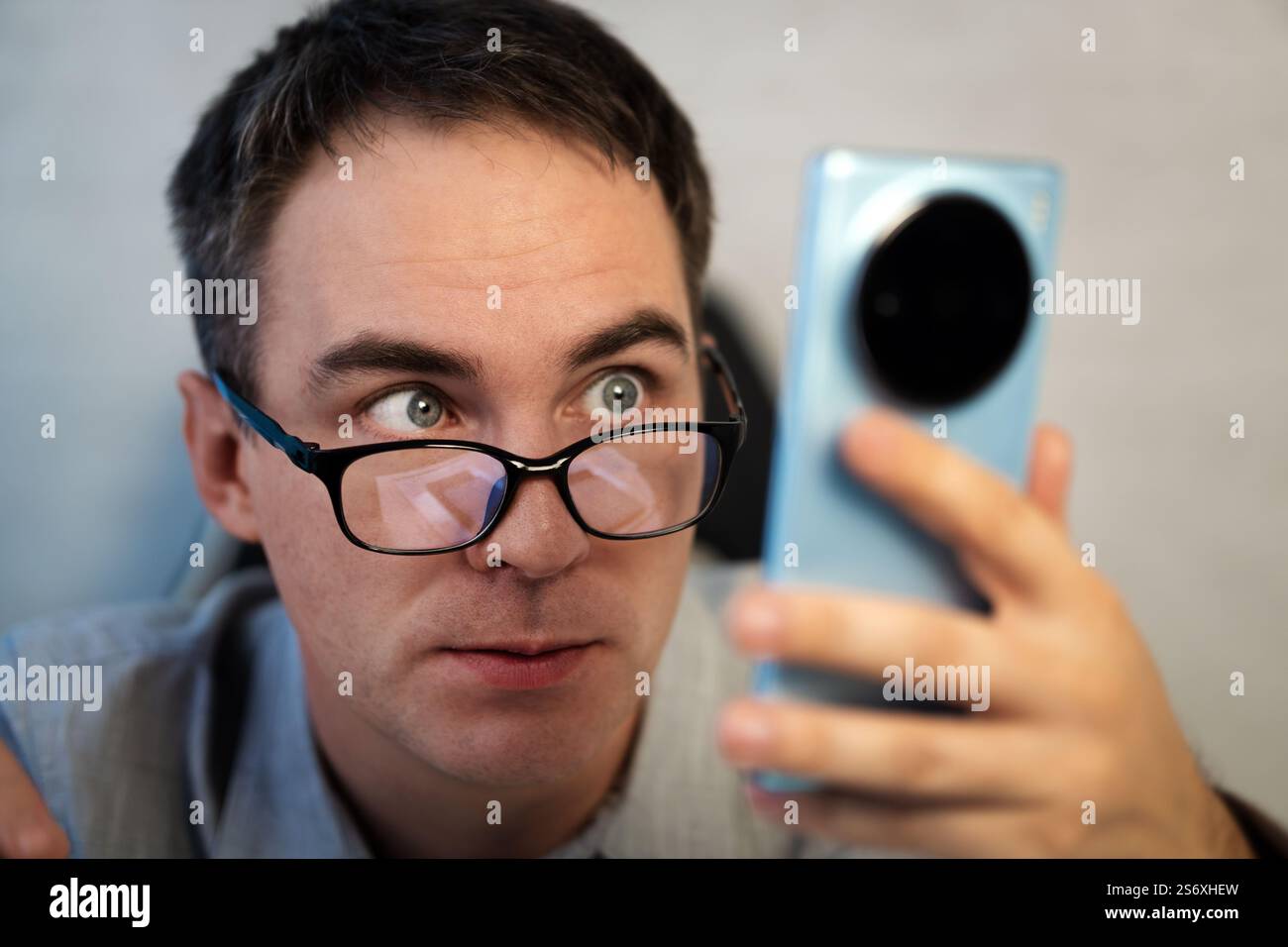 A young beautiful man with a phone in his hands opens his eyes wide ...