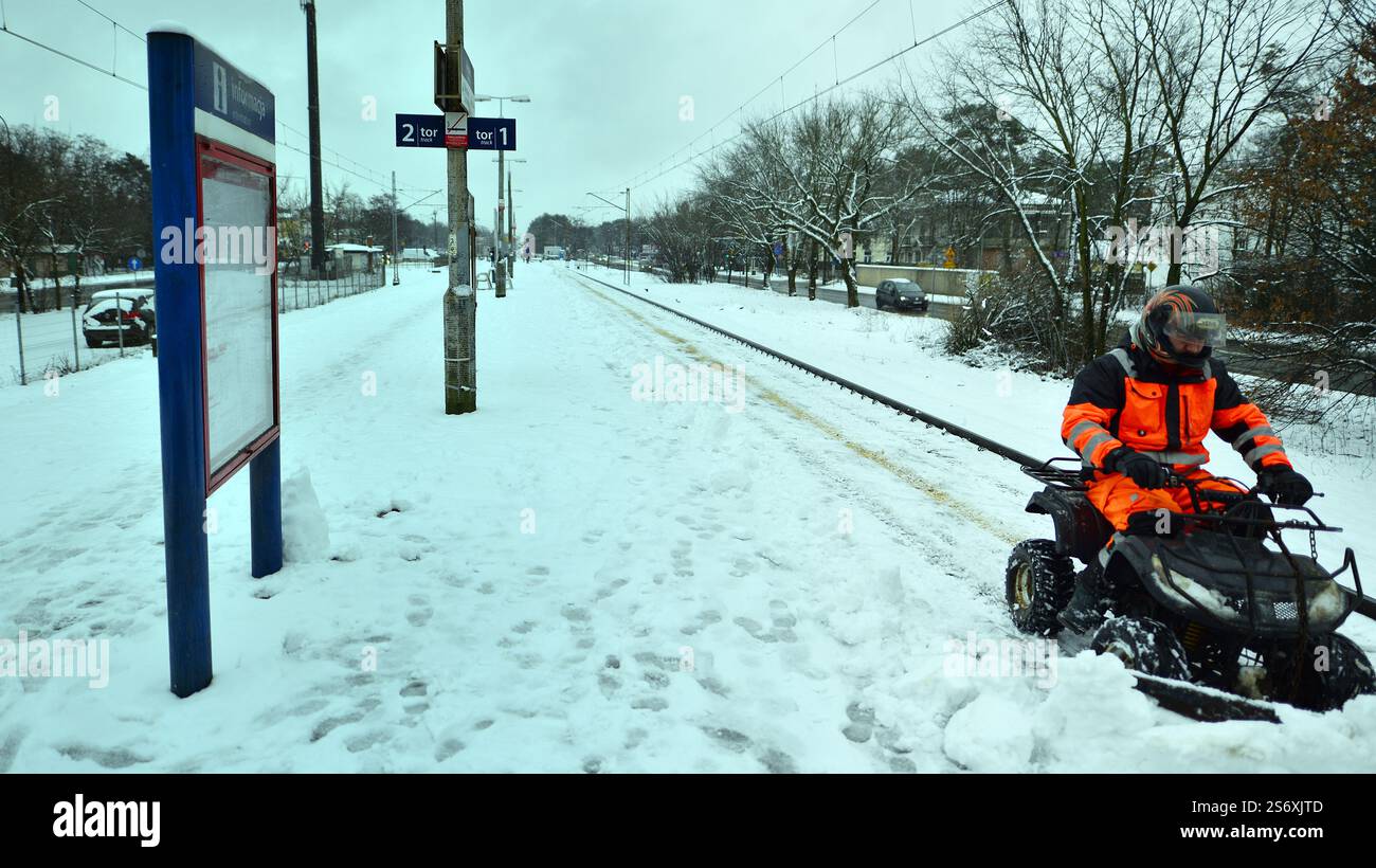 Warsaw, Poland. 12 January 2025. A worker sweeps snow at the railway ...