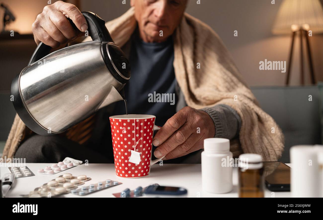 Senior man pouring boiling water from a metal kettle preparing tea ...