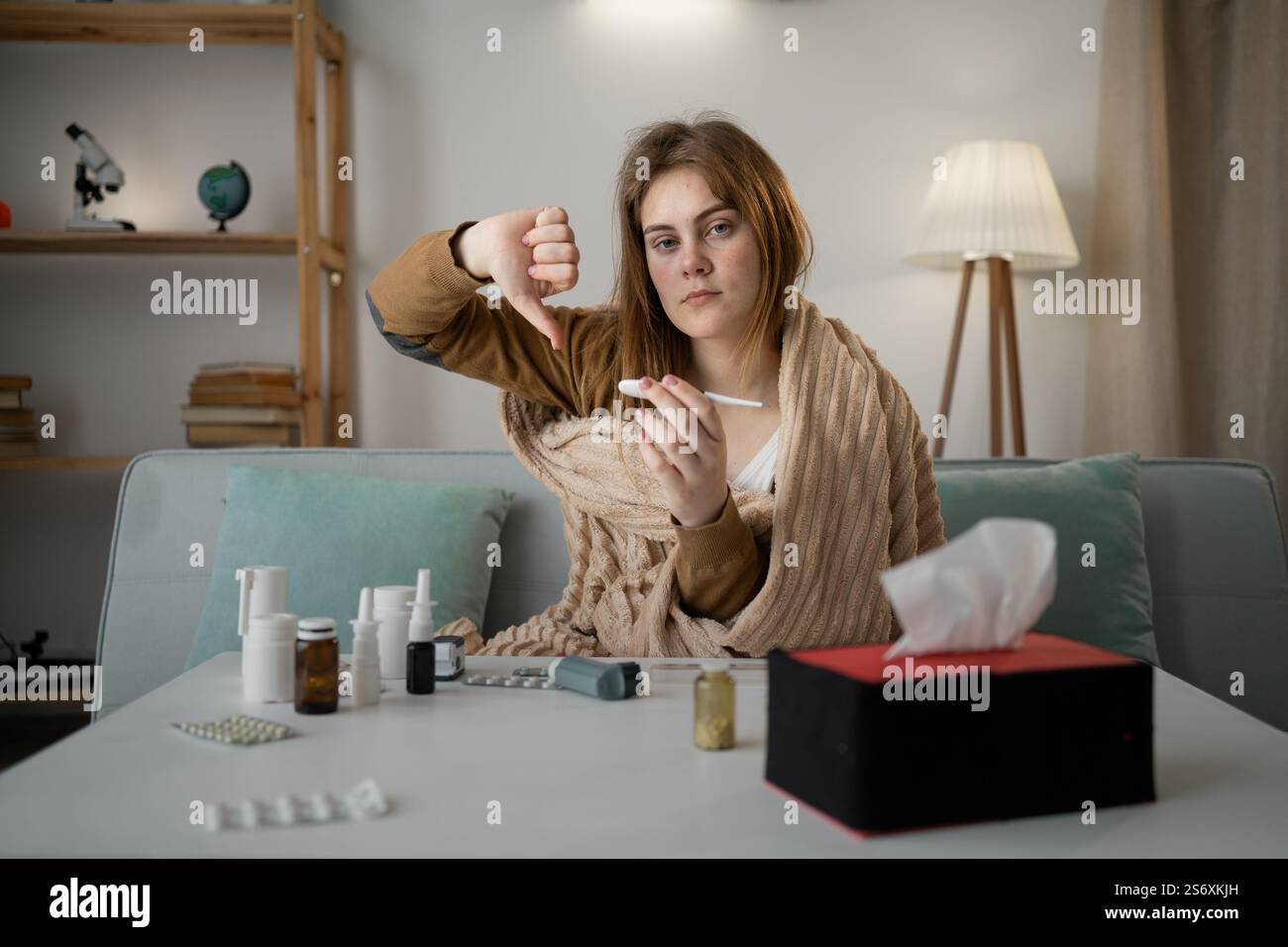 Woman with flu and fever in living room on sofa. Young lady showing bad ...
