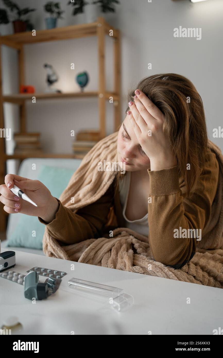 An unhappy young woman suffering from flu, fever and headache looks ...