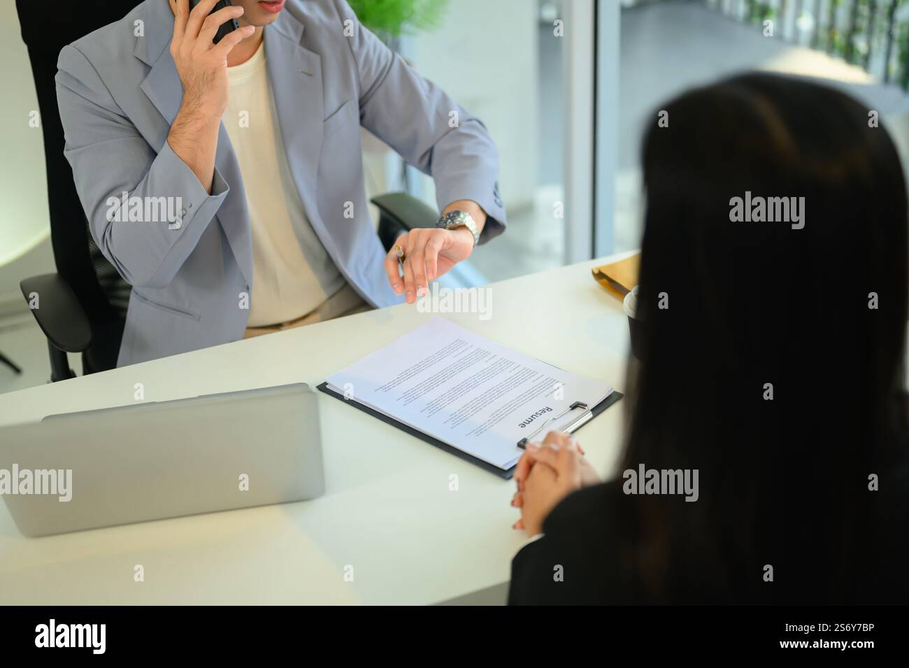 Recruiter speaking on the phone while reviewing a candidate resume ...