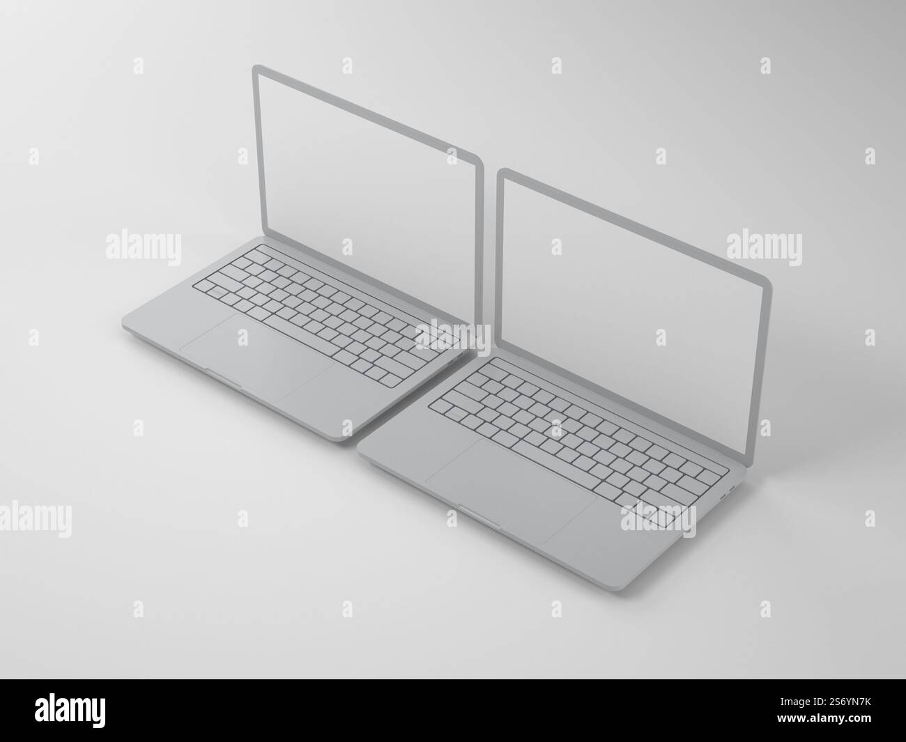 Two open modern gray laptops with blank screens on a light background ...