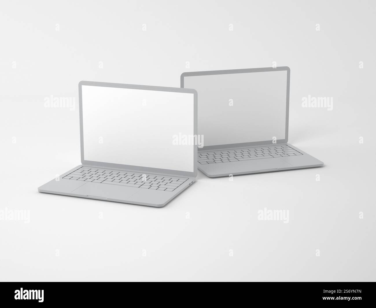 Two open modern gray laptops with blank screens on a light background ...