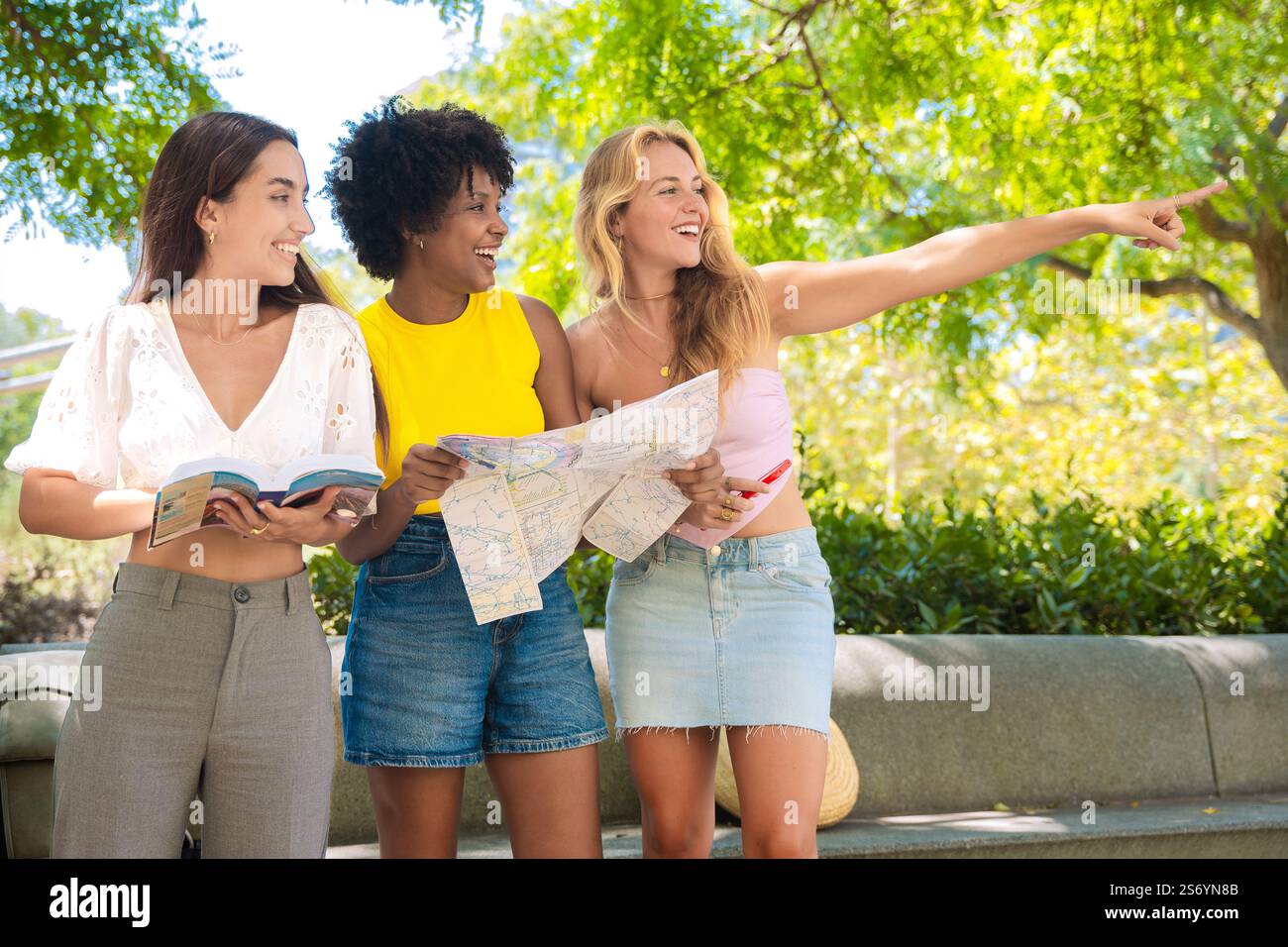 Three young women exploring the city with maps and a travel guide ...