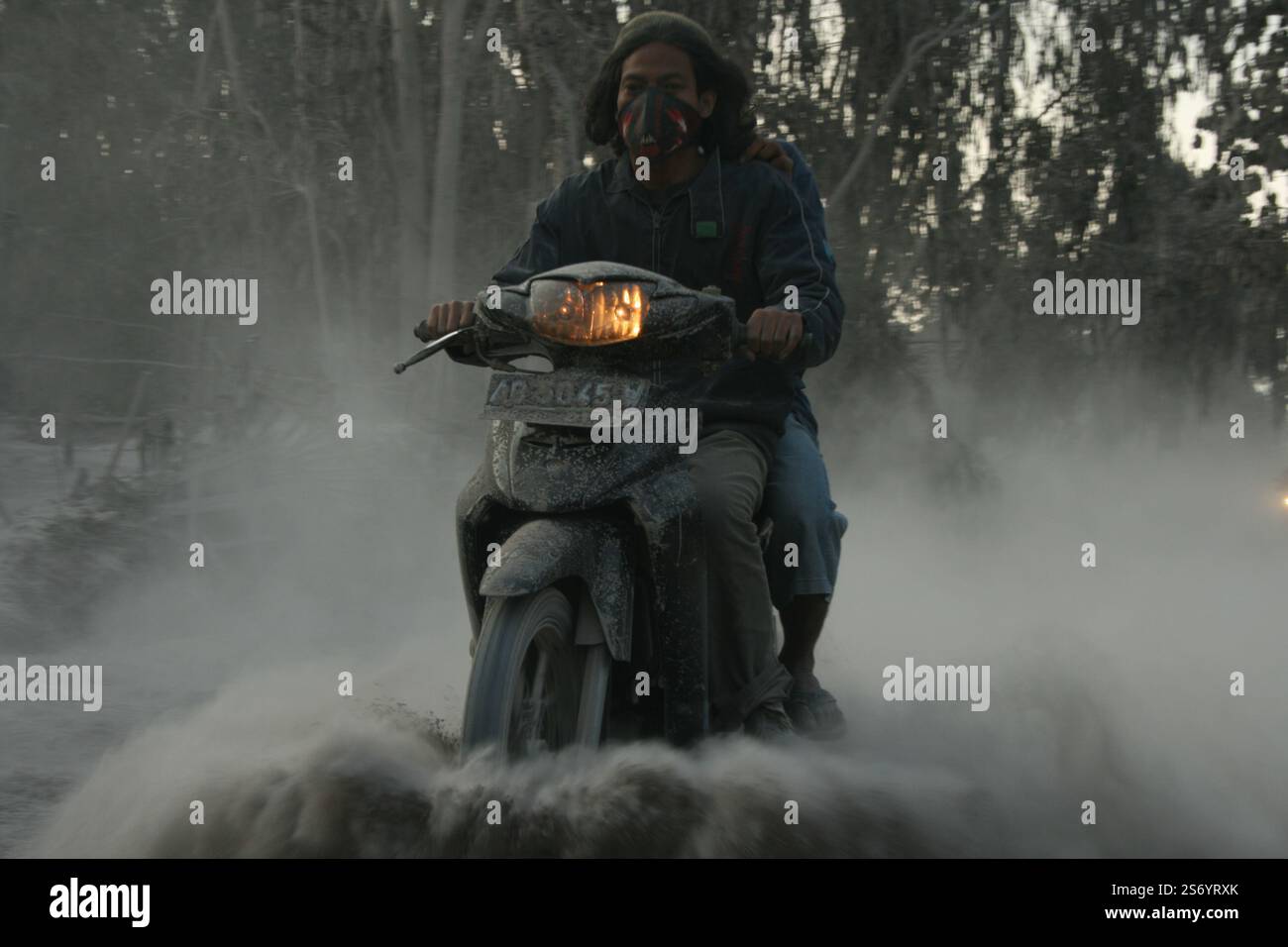 Motorcyclists ride a road covered in thick volcanic ash after the ...