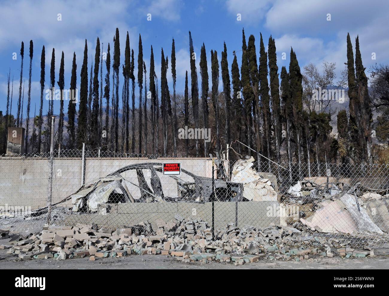 A burned car sits amid the rubble of a house destroyed in the Eaton ...