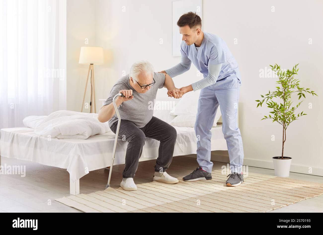 Caregiver helping an elderly patient with health problems to get up ...