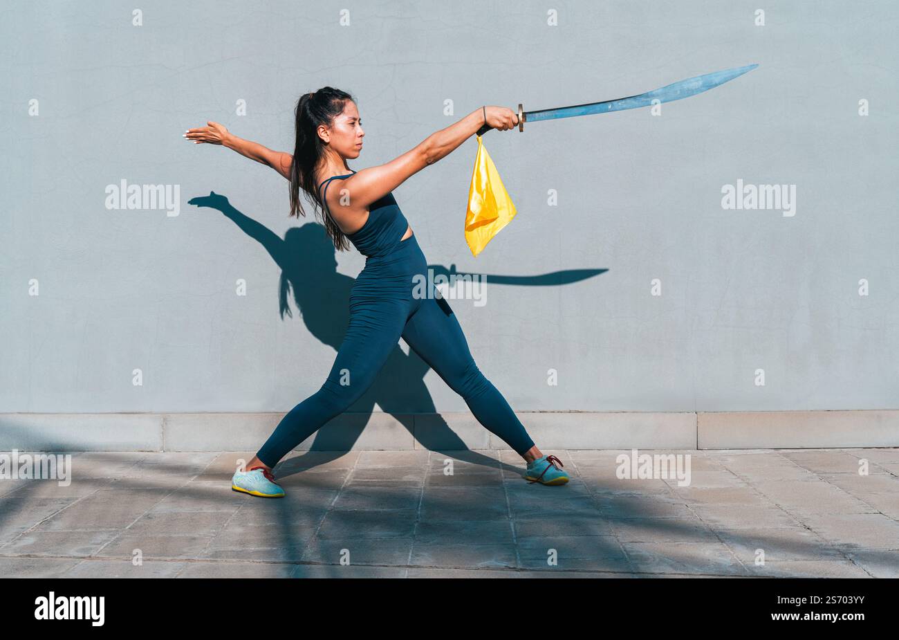 Chinese young woman practicing wushu kung fu with weapons outdoor. Young girl training martial ...