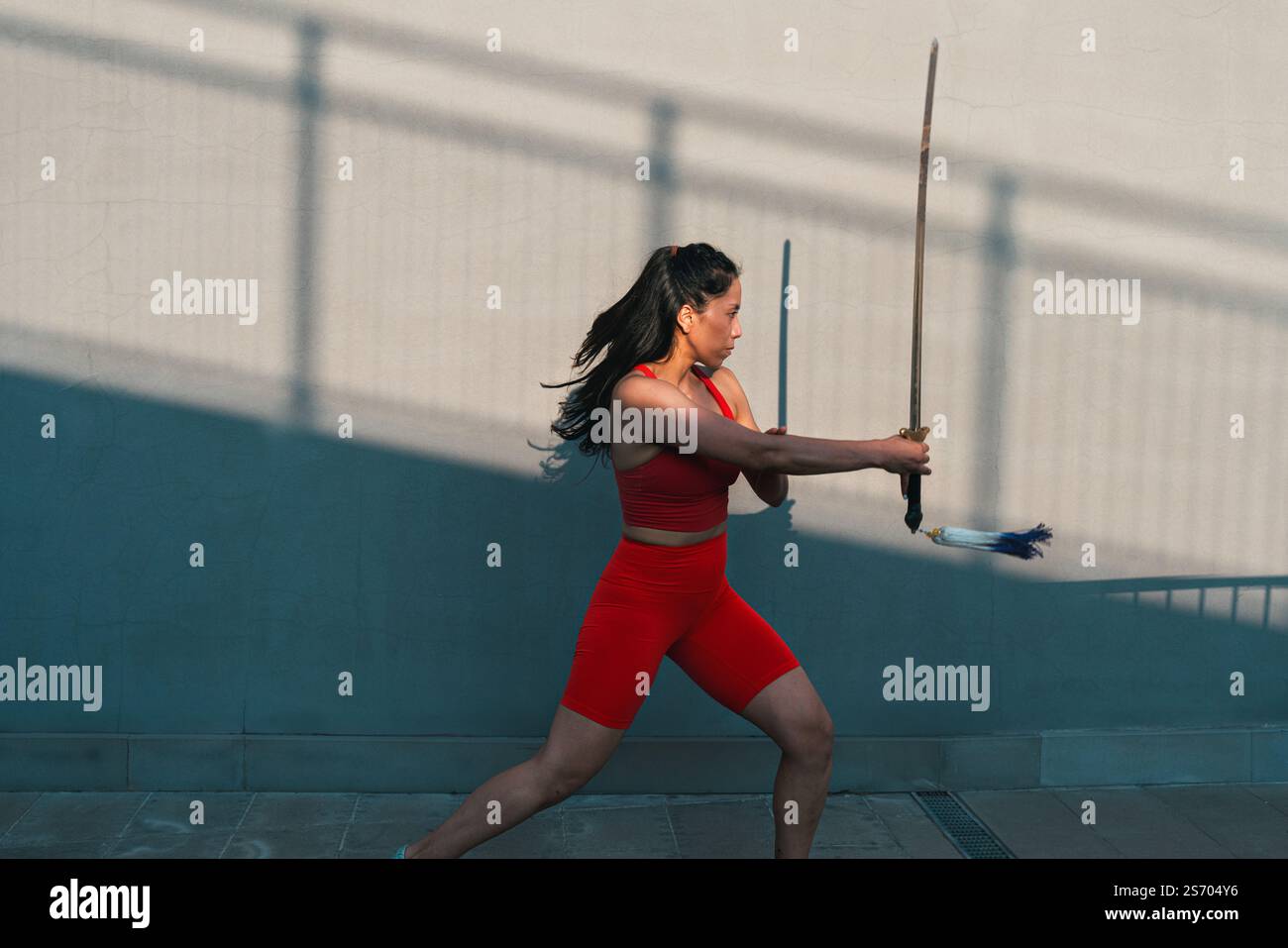 Chinese young woman practicing wushu kung fu with weapons outdoor. Young girl training martial ...