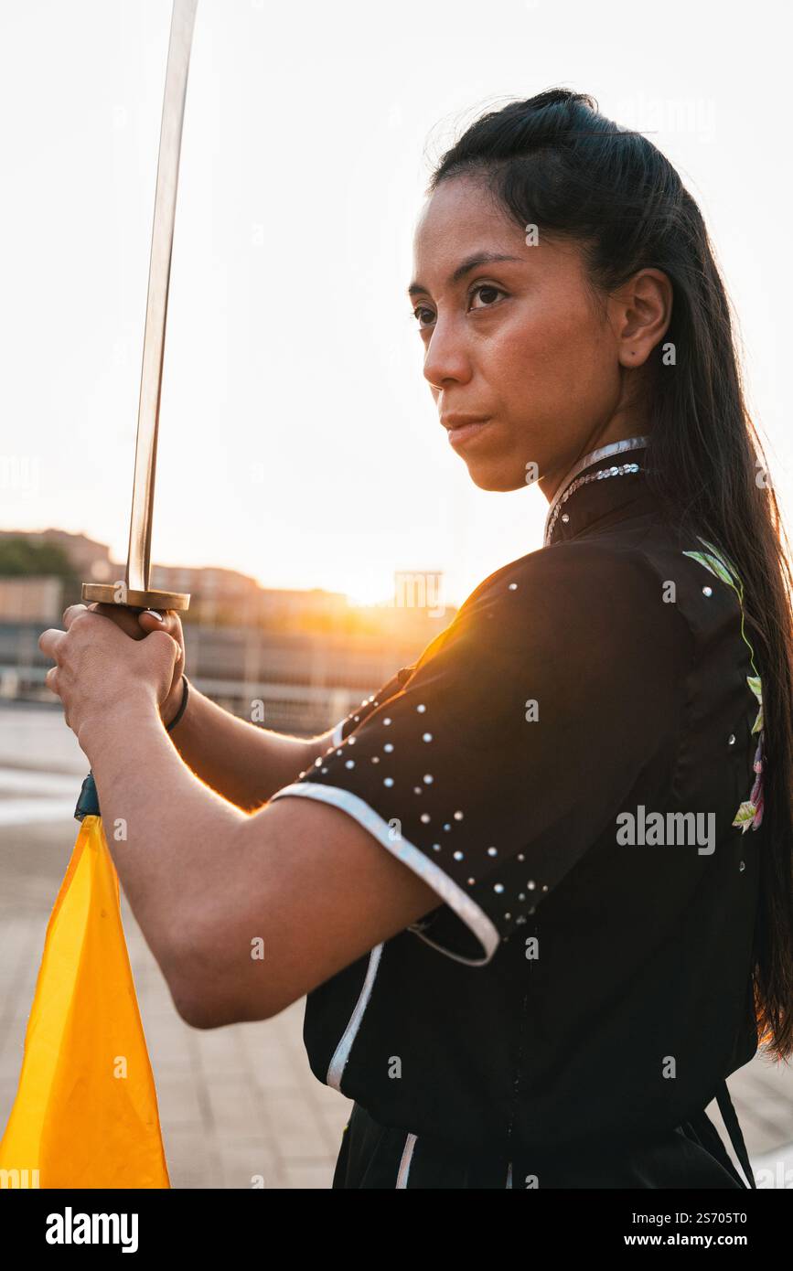 Chinese young woman practicing wushu kung fu with weapons outdoor. Young girl training martial ...