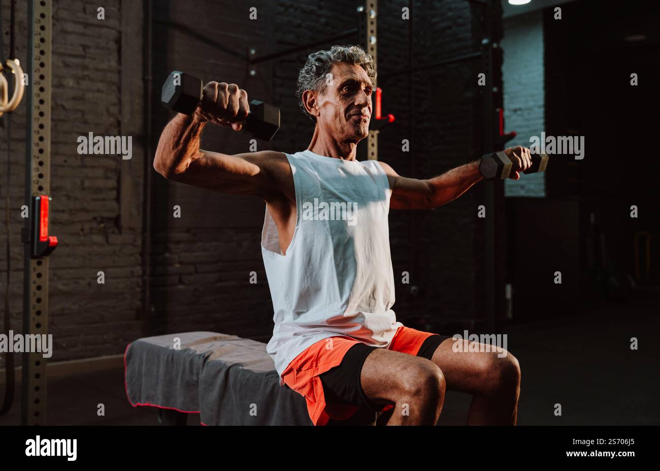 Fit senior man in the gym training with weights. Man with dumbbells ...