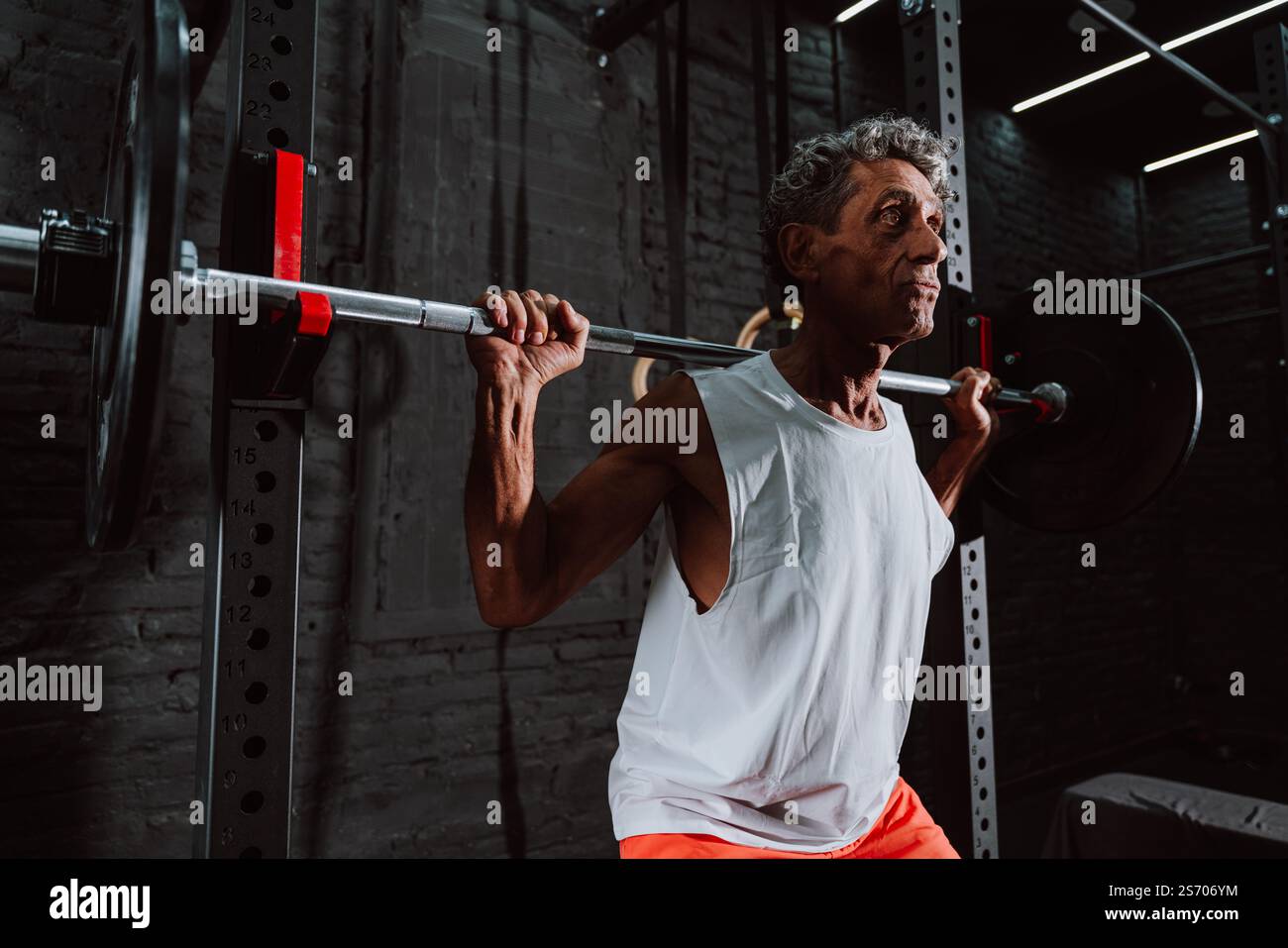 Fit senior man in the gym with his personal trainer, learning the squat ...