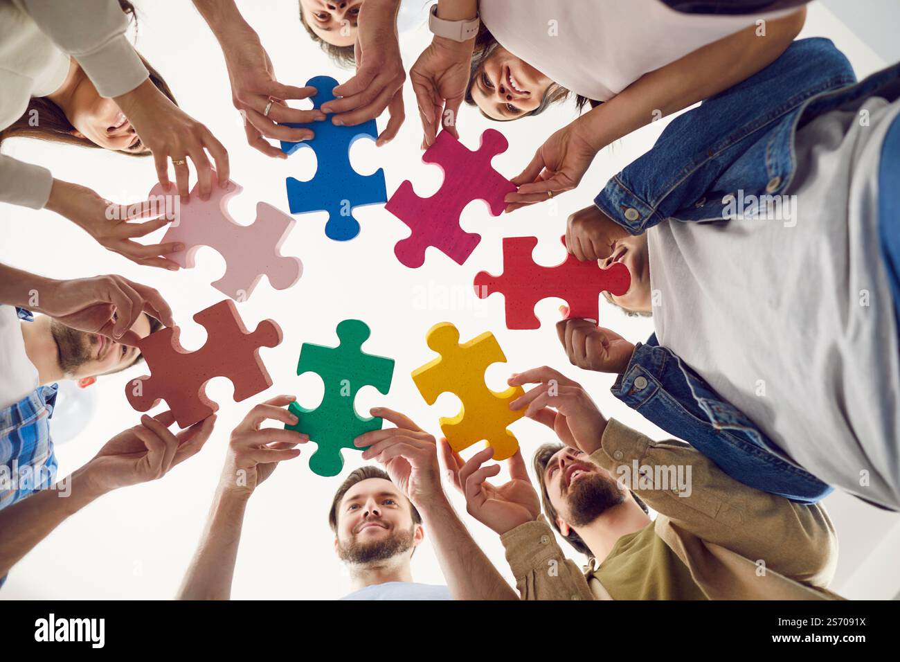 Bottom view of a happy smiling people putting together pieces of big ...