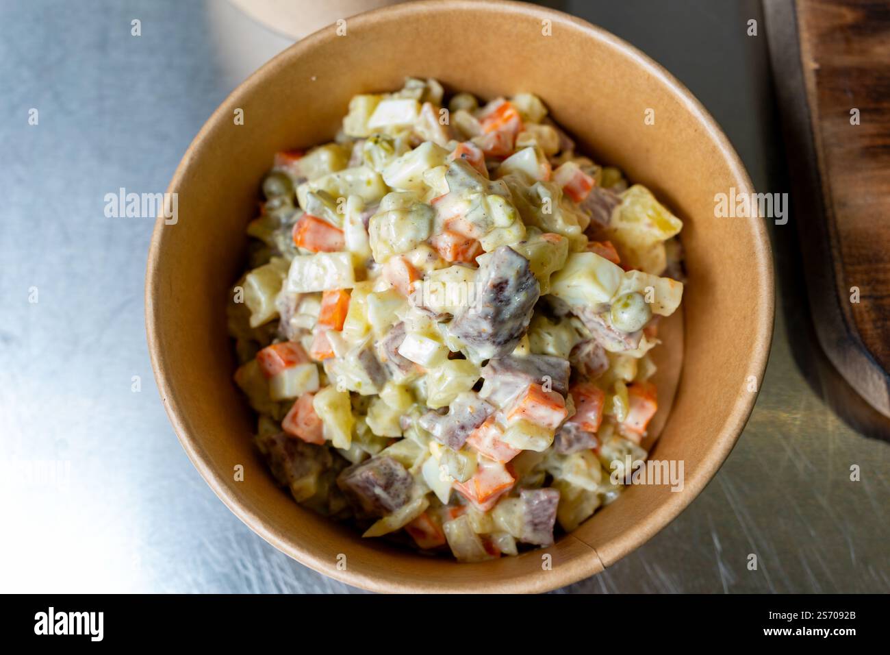 A vibrant bowl of Russian salad filled with diced vegetables, pickles ...