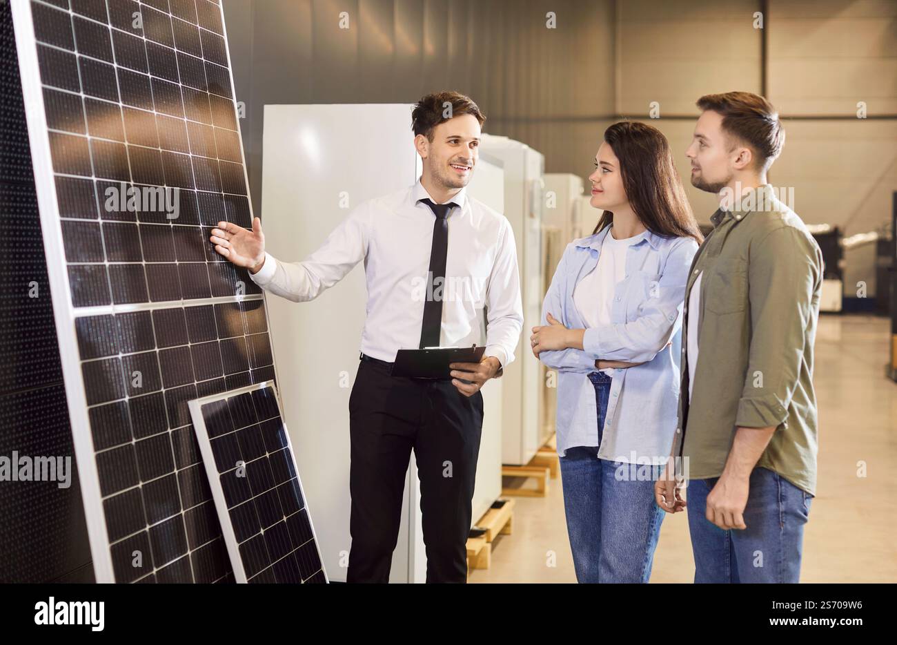 Young smiling solar panels seller consulting family couple standing in ...