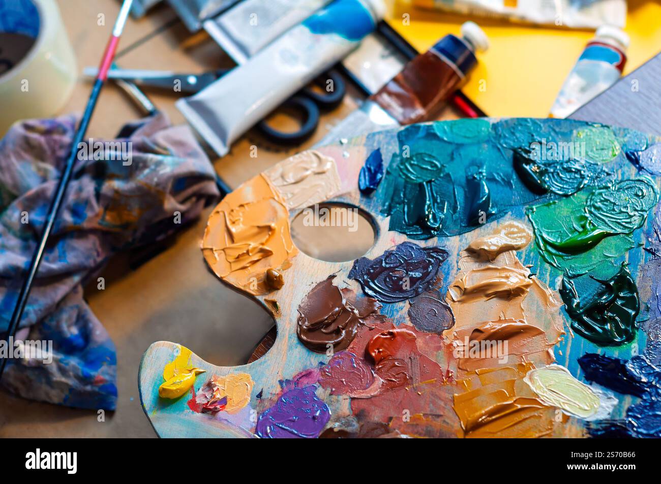 Close-up of a painters workspace featuring a colorful palette, tools ...