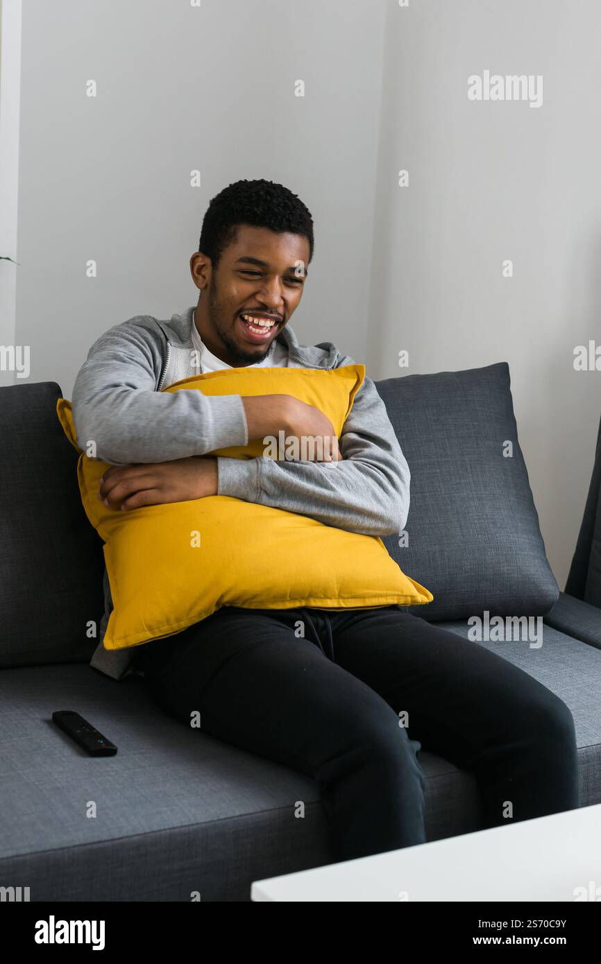 African american man focuses on the television while eating popcorn, fully immersed in show ...
