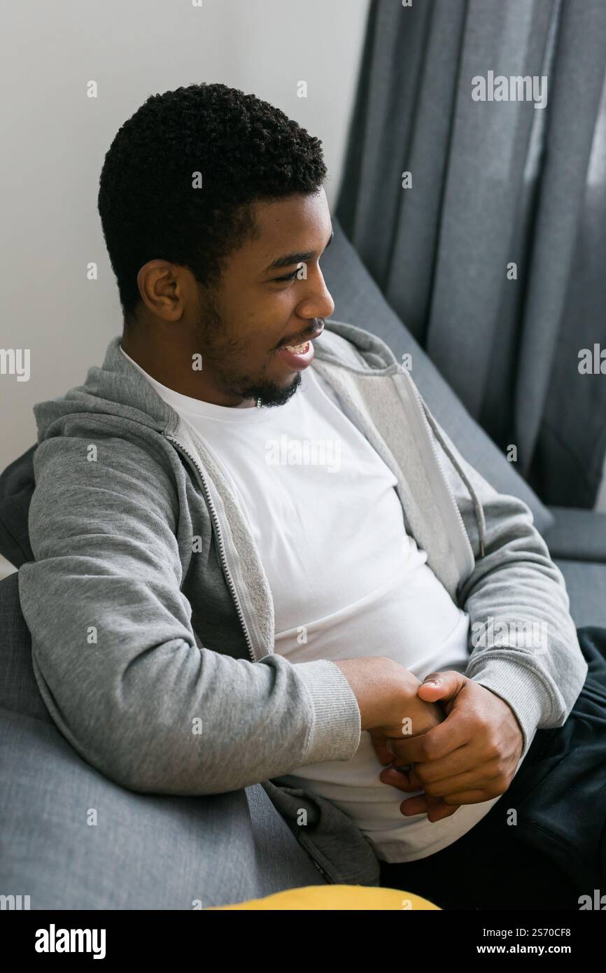 African american man focuses on the television while eating popcorn, fully immersed in show ...