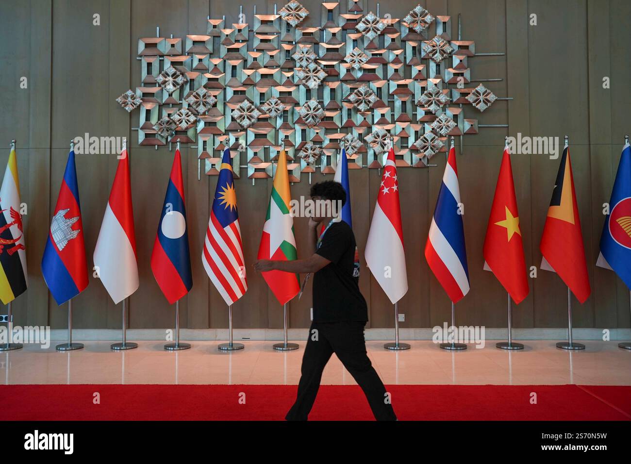 A man walk past the flags of the Association of Southeast Asian Nations ...