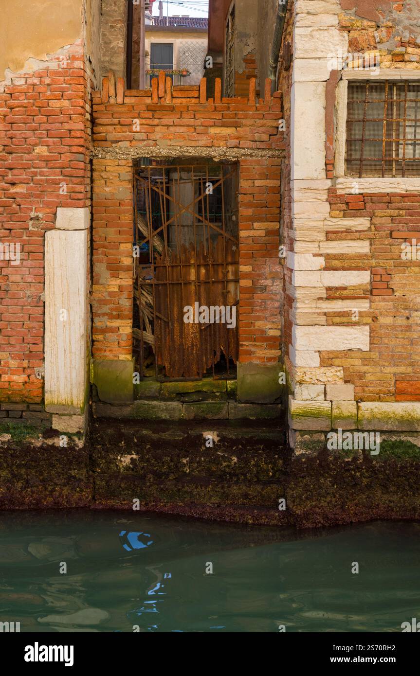 Venetian canal-side building, showing weathered brickwork, a rusty ...