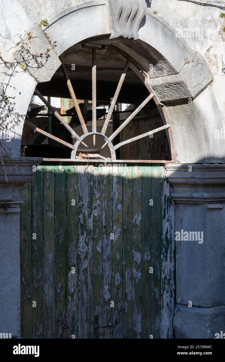 Weathered, arched stone doorway with a decaying green wooden door and ...