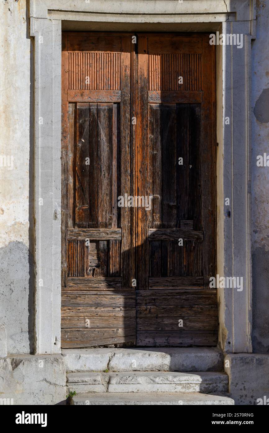 Weathered wooden door set in a stone building with steps. Aged wood and ...