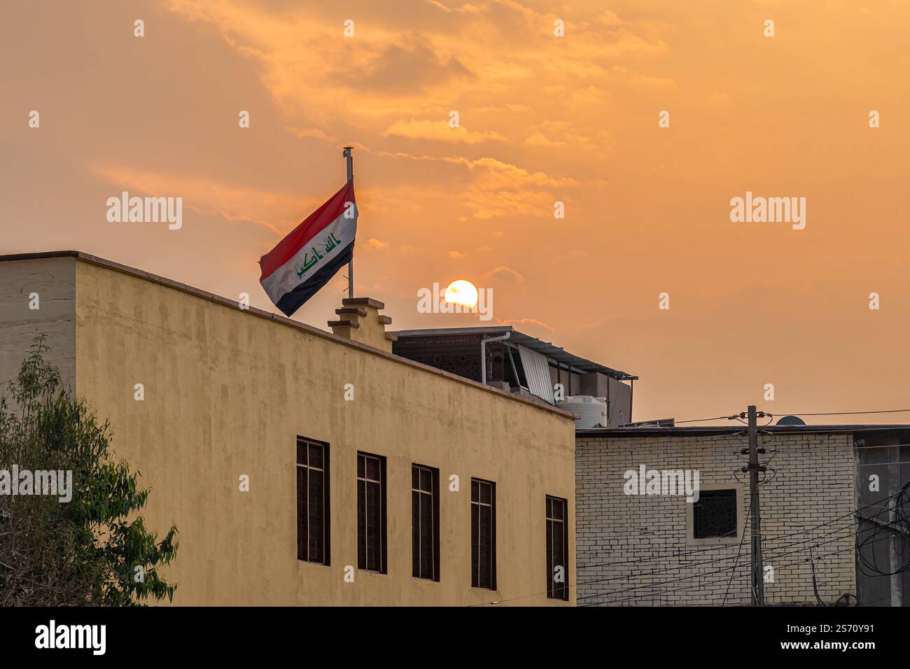 Sunset in Basra, Iraqi flag on a building Stock Photo - Alamy