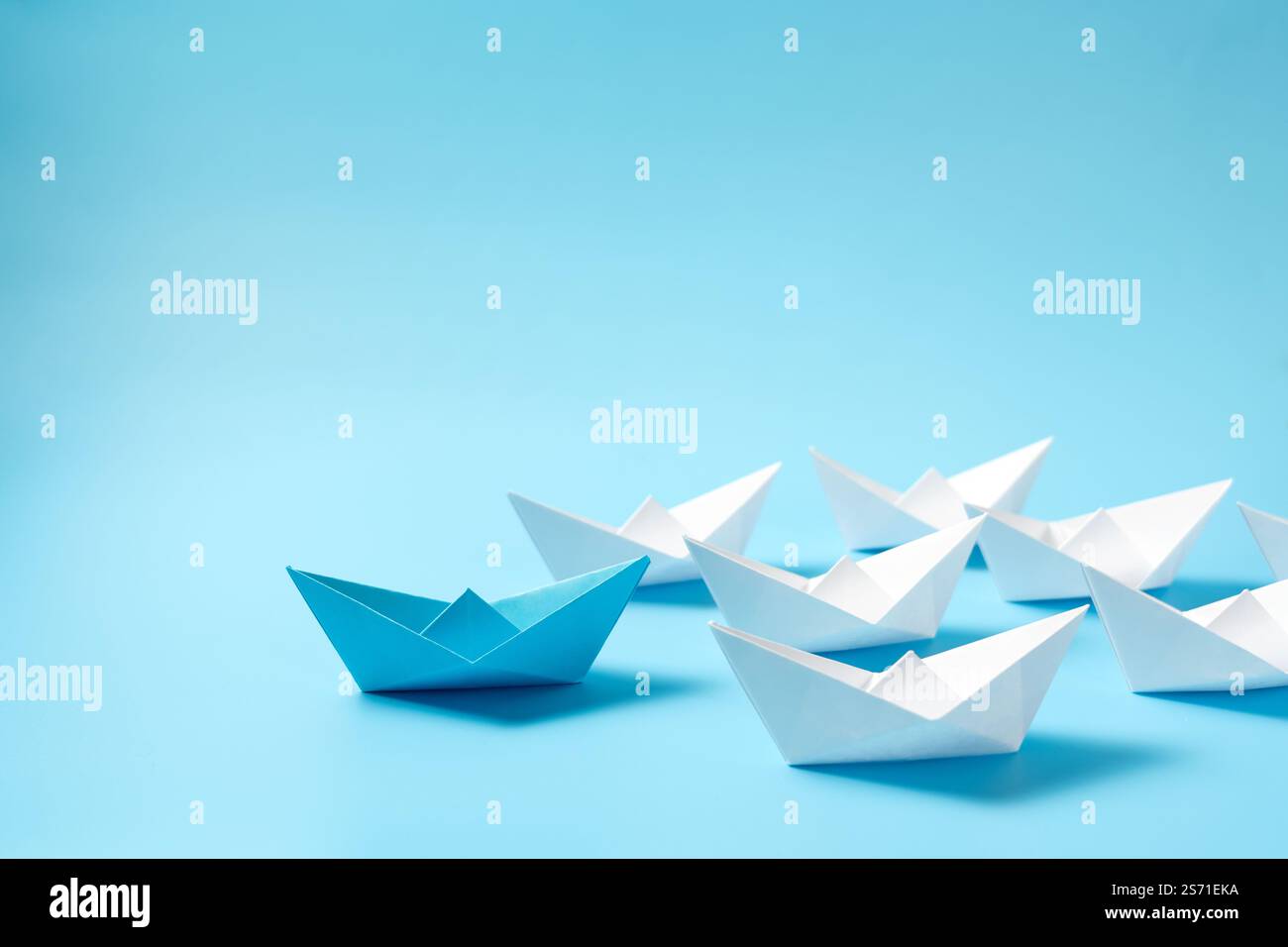 Leadership concept with blue paper ship leading among white boats ...