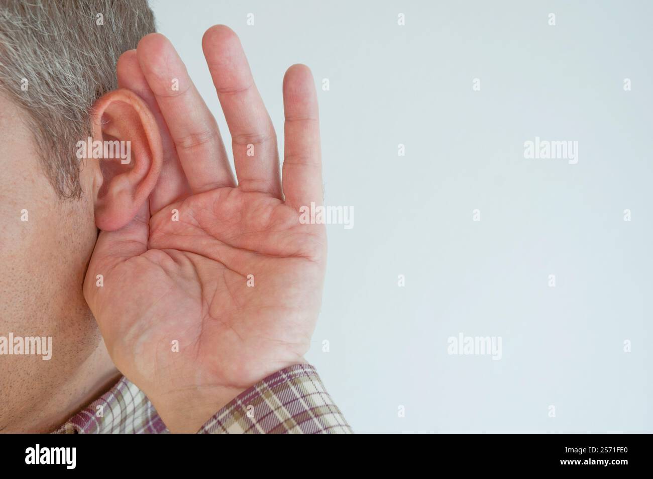 Deaf man holding his hand behind his ear to amplify sound. Close view ...