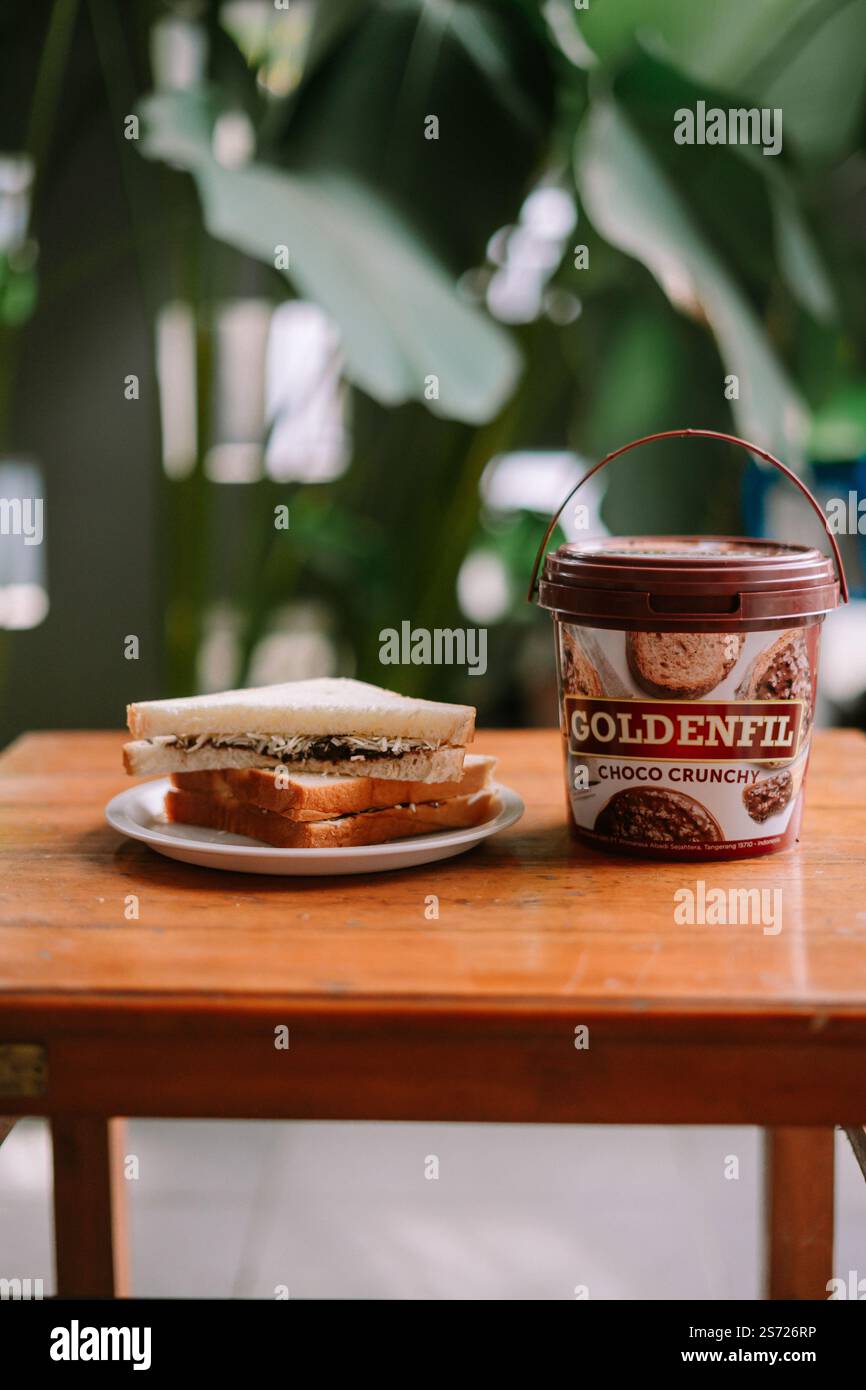 A simple sandwich sits next to a container of chocolate crunchy spread ...