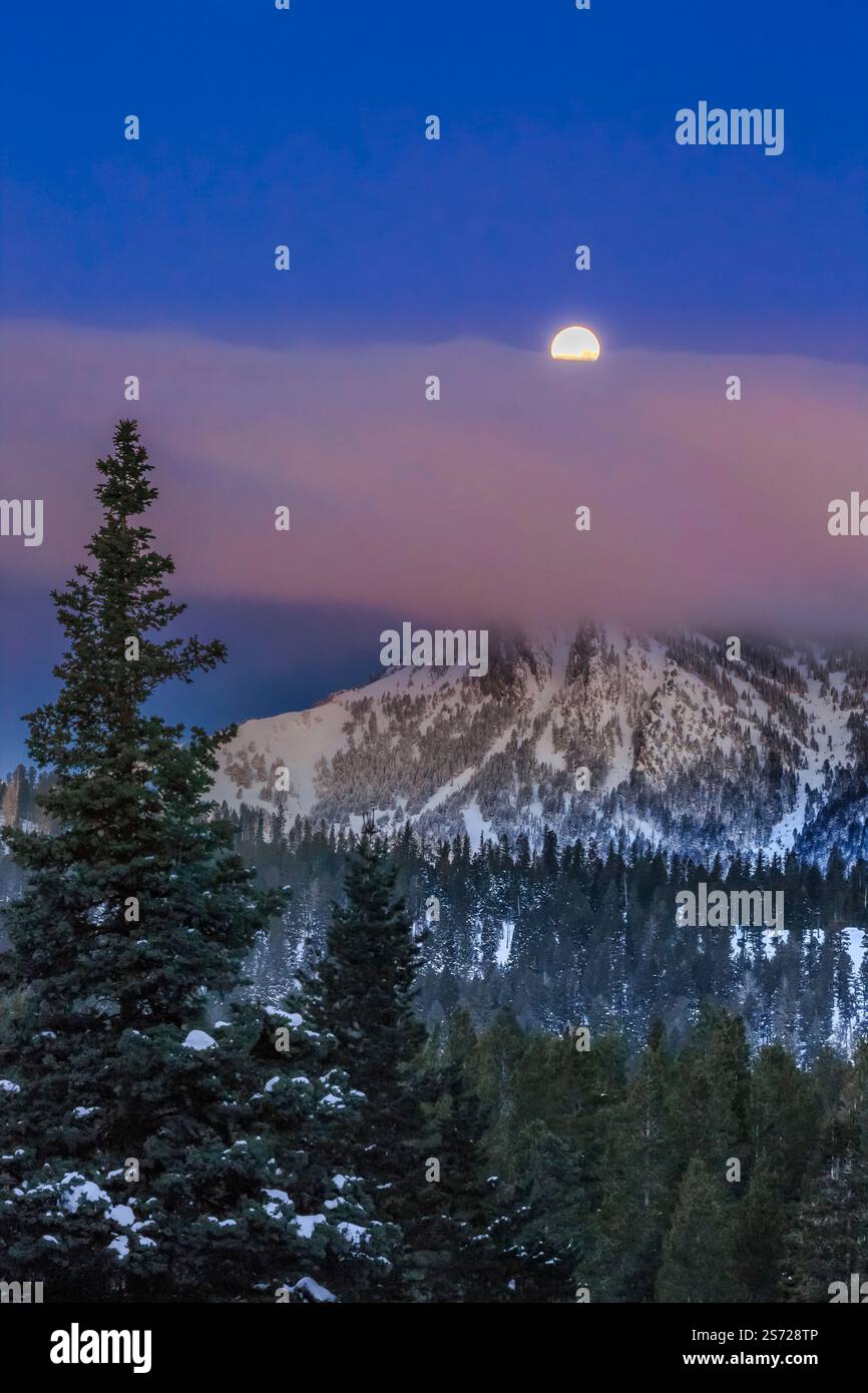 full moon setting into a cloud bank above ross peak in the bridger ...