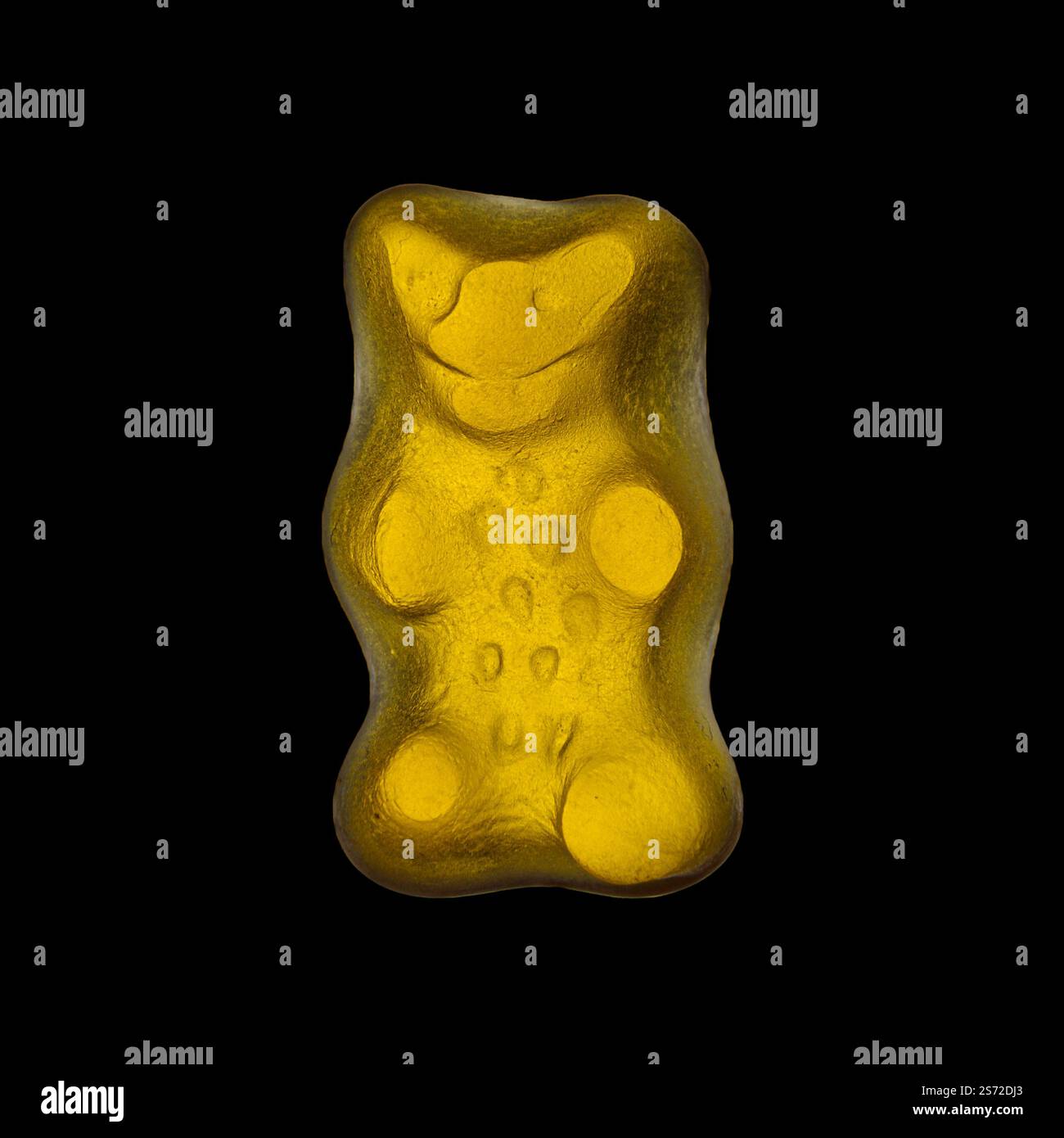 A detailed close-up image of a yellow gummy bear isolated on a black ...