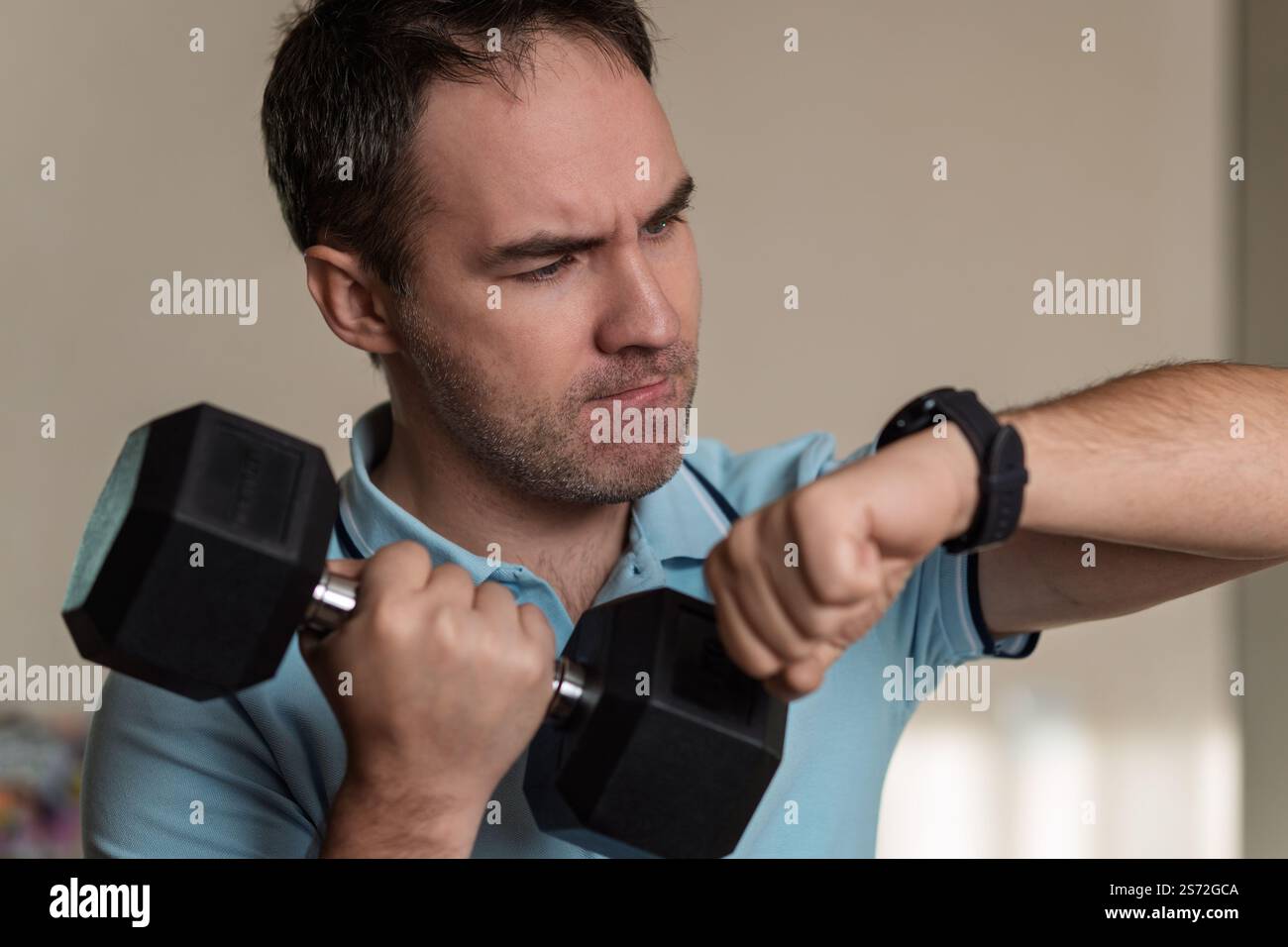 Male hand with a fitness bracelet clock holds a dumbbell, biceps ...