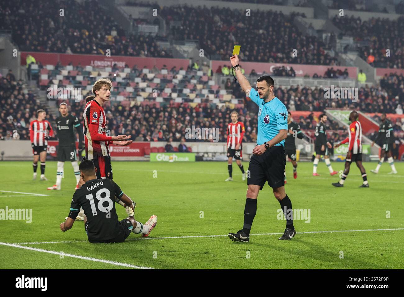 Referee Andy Madley gives a yellow card to Mads Roerslev of Brentford ...